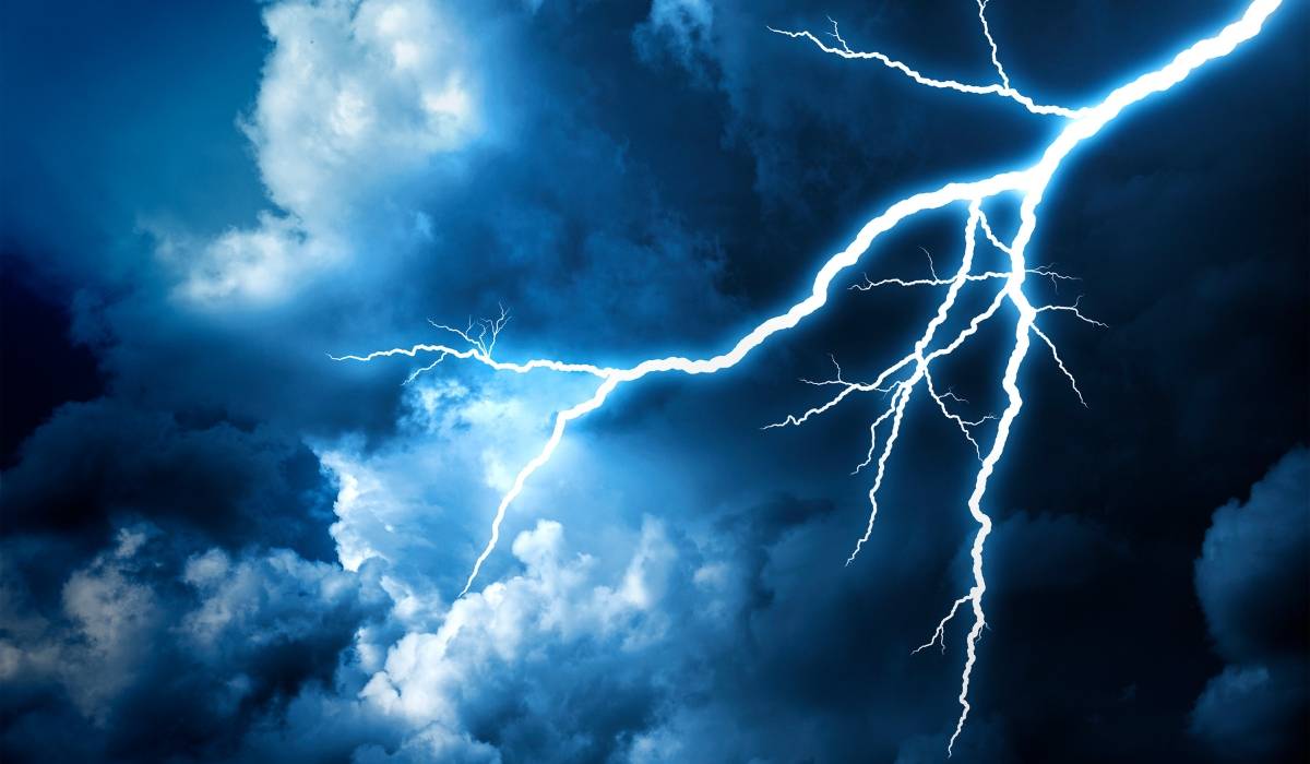 Bright blue lightning forks across a dark, cloudy sky, illustrating the ...
