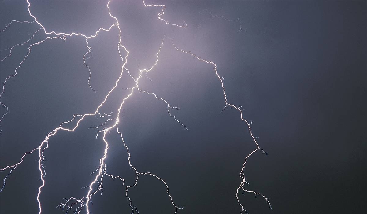 Bright, branching lightning streaks across a dark night sky ...